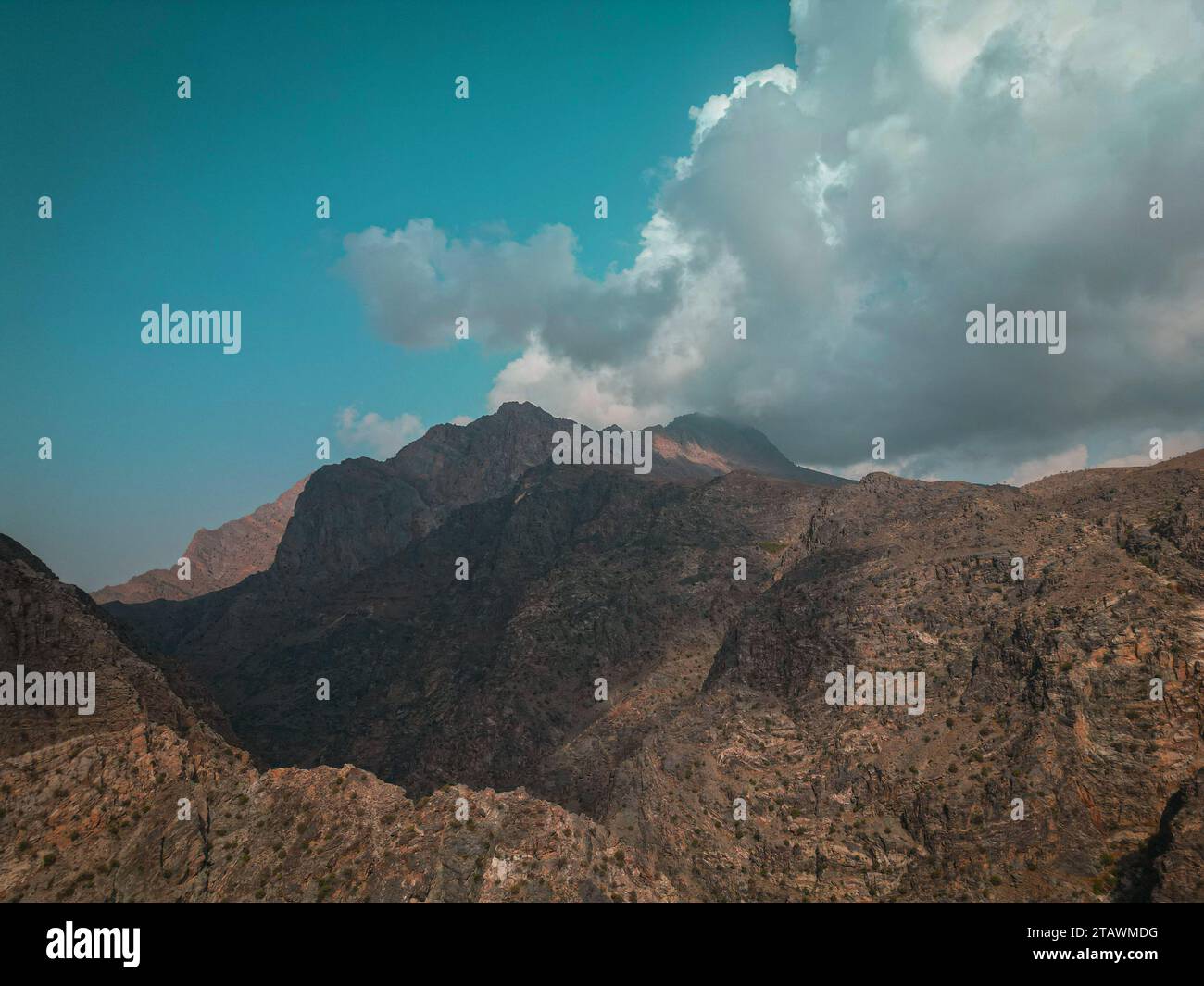 An aerial view of mountains with a blue sky and a road crossing through ...