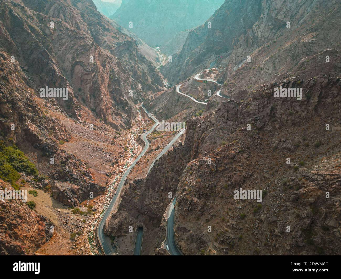 An aerial view of mountains with a blue sky and a road crossing through ...