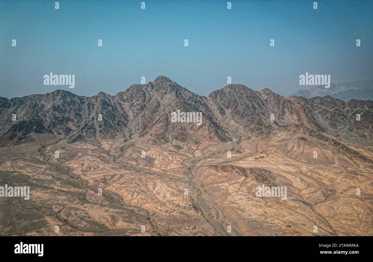An aerial view of mountains with a blue sky and a road crossing through ...