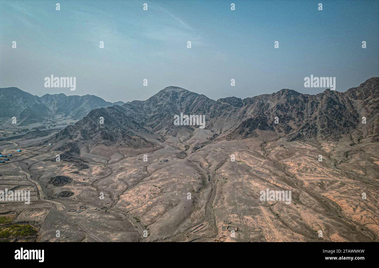 An aerial view of mountains with a blue sky and a road crossing through ...