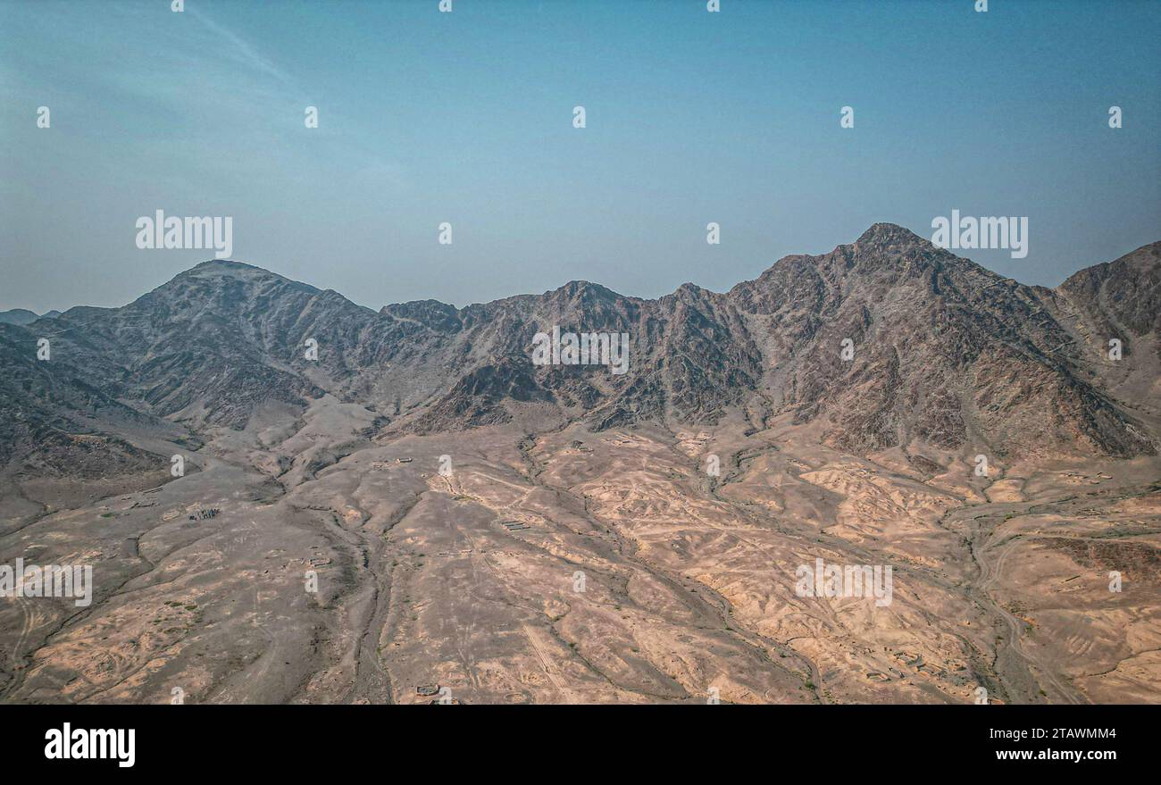 An aerial view of mountains with a blue sky and a road crossing through ...