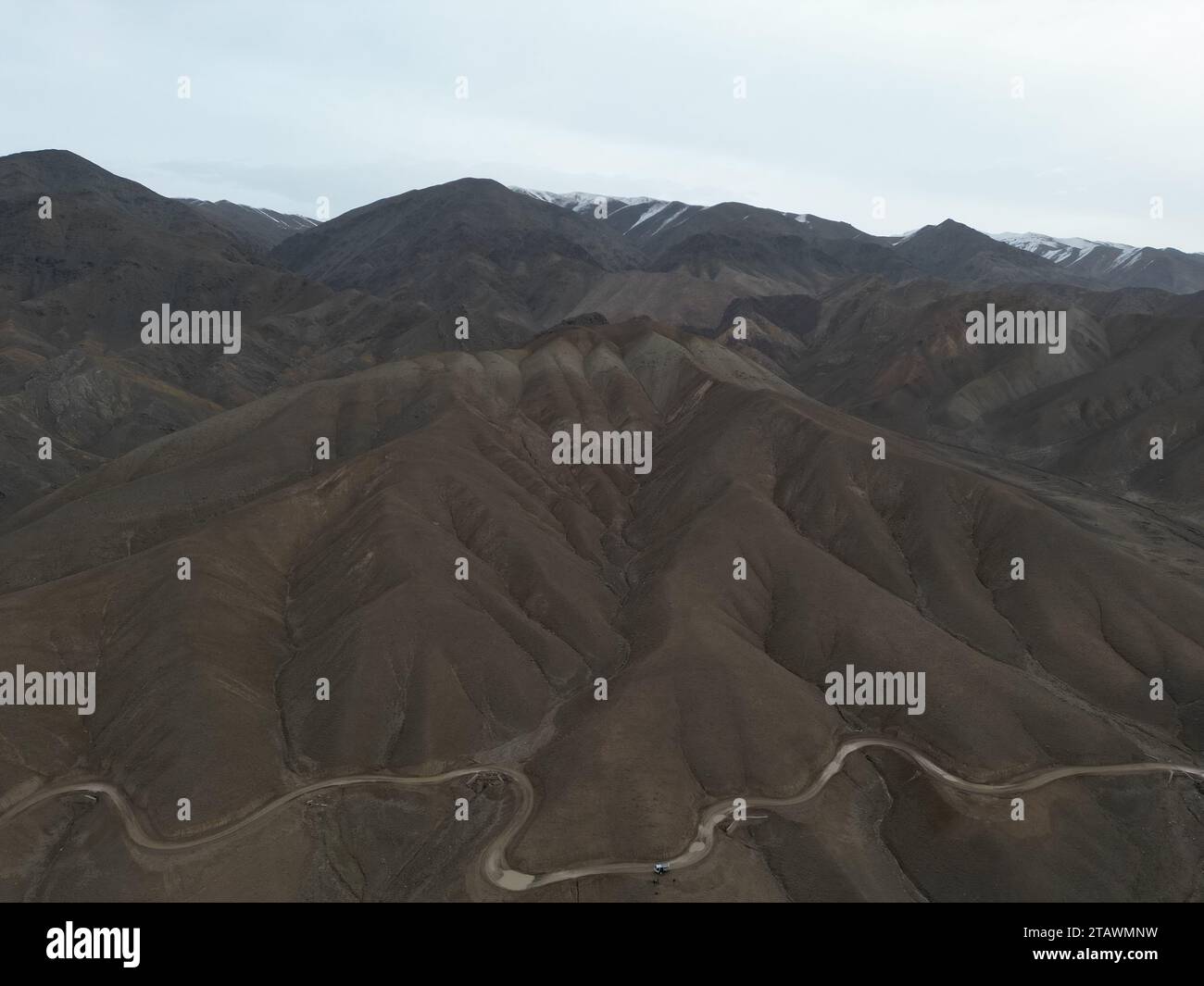 An aerial view of mountains with a blue sky and a road crossing through ...