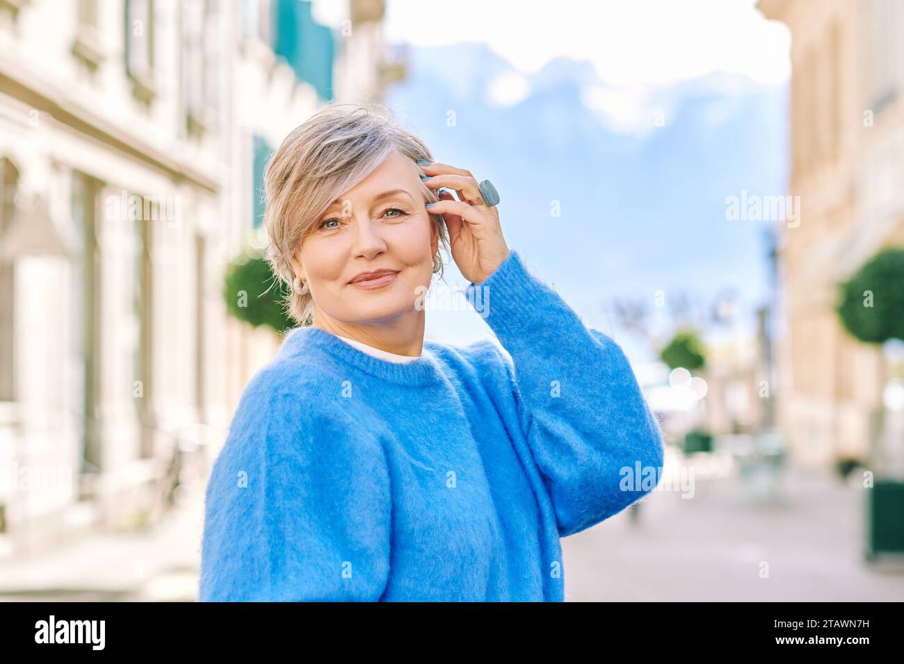 Outdoor portrait of beautiful middle age 55 - 60 year old woman posing outside, wearing blue ...