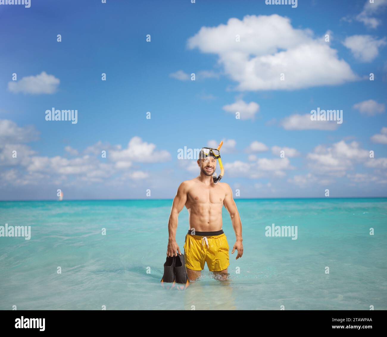 Man in a swimsuit with a diving mask holding snorkeling fins and ...