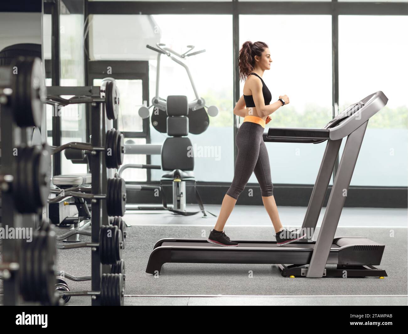 Full length profile shot of a woman walking on a treadmill at the gym ...