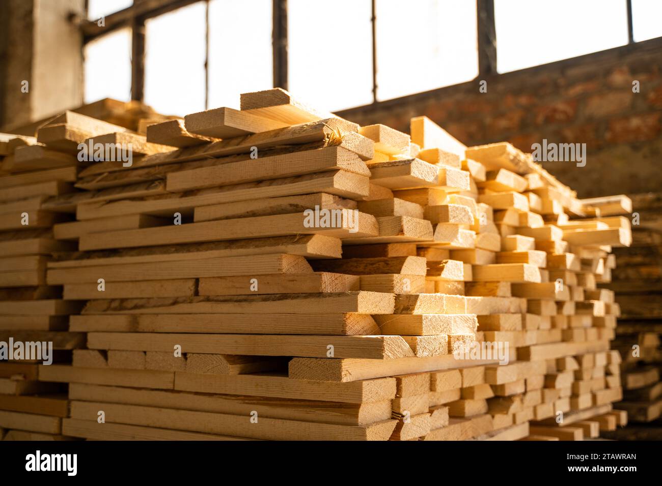 Stacked raw wooden planks at a indoor lumber warehouse. Background of ...