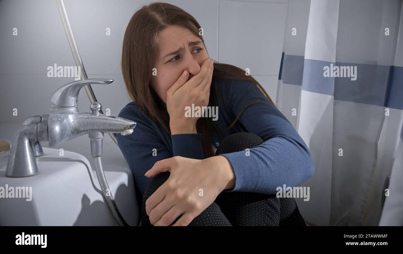 Afraid woman woman hiding in bathroom from criminal and closing her ...