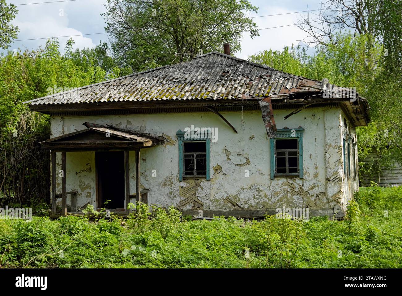 A house in a state of disrepair, with a collapsing roof and peeling paint, is captured in the ...