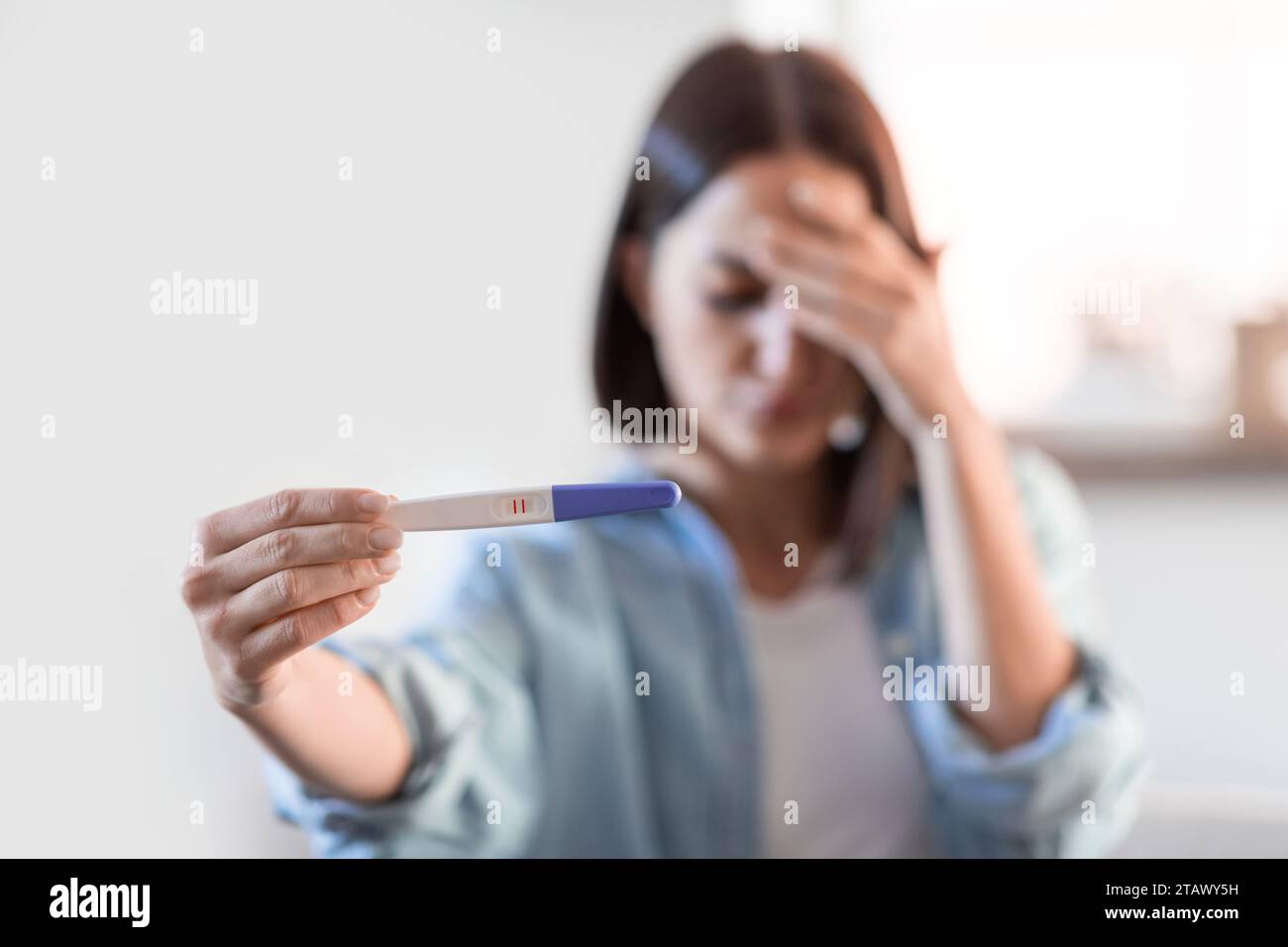 Upset lady holding positive pregnancy test at home, covering face Stock ...