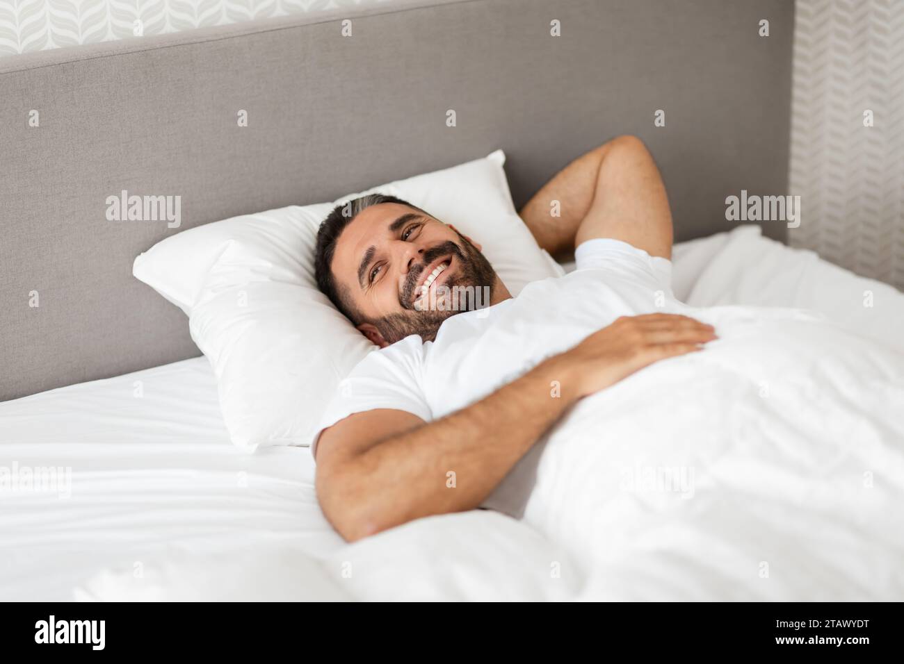 Happy Guy Lying Awake Resting In Comfortable Bed In Bedroom Stock Photo ...
