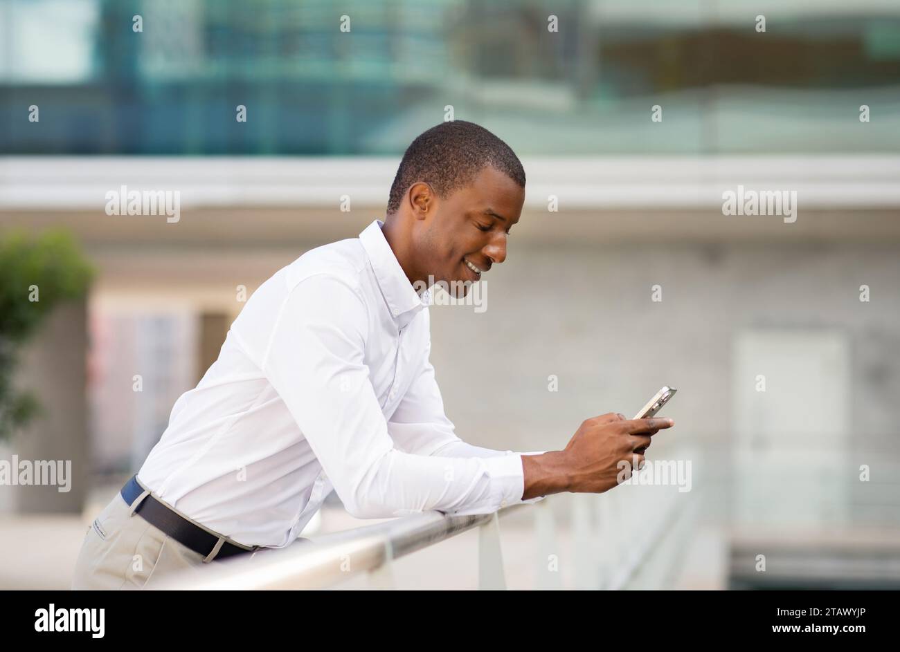 Smiling Black Businessman Leaning At Railing And Using Smartphone ...