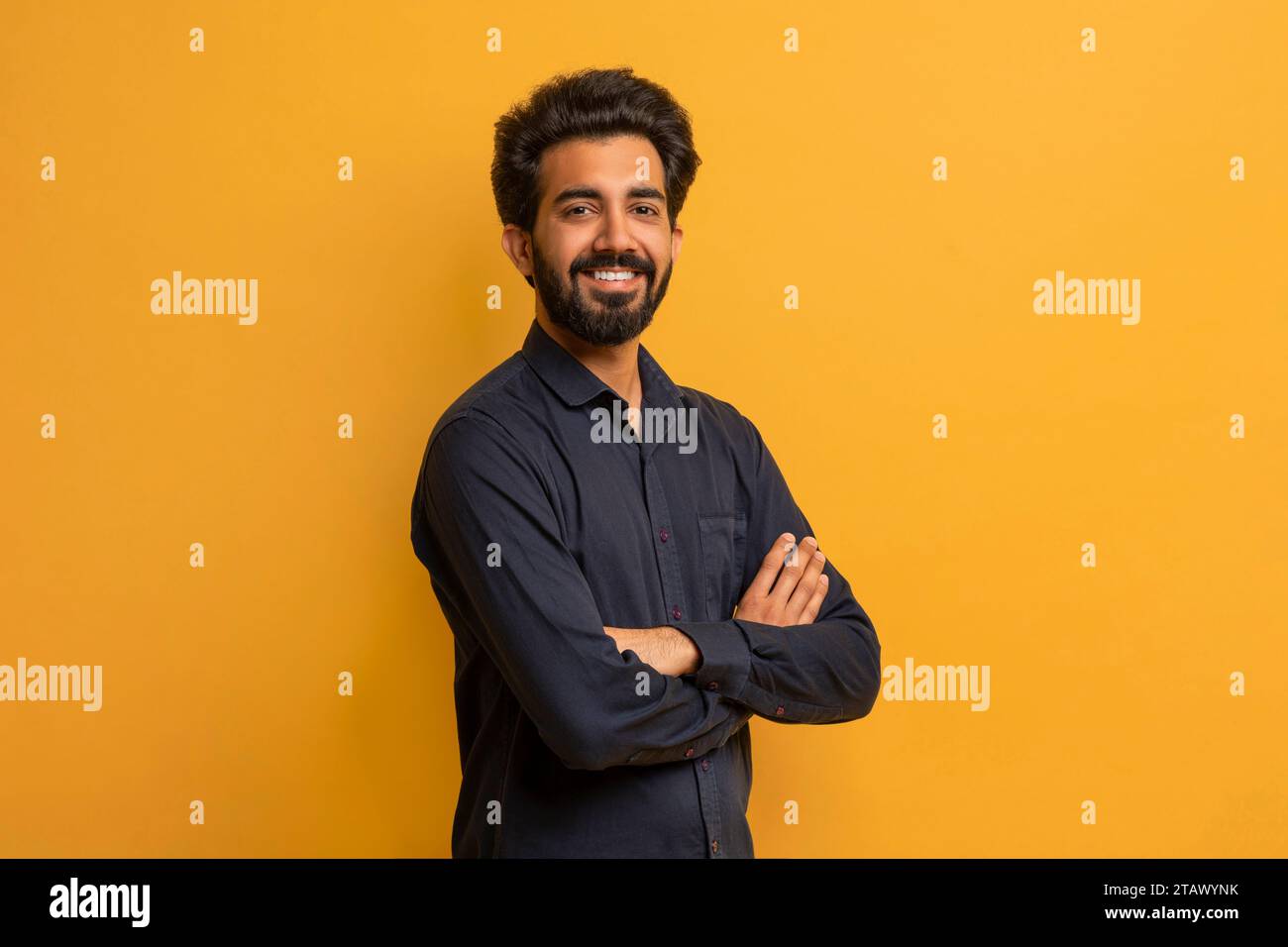 Confident young indian man standing arms crossed over yellow background ...