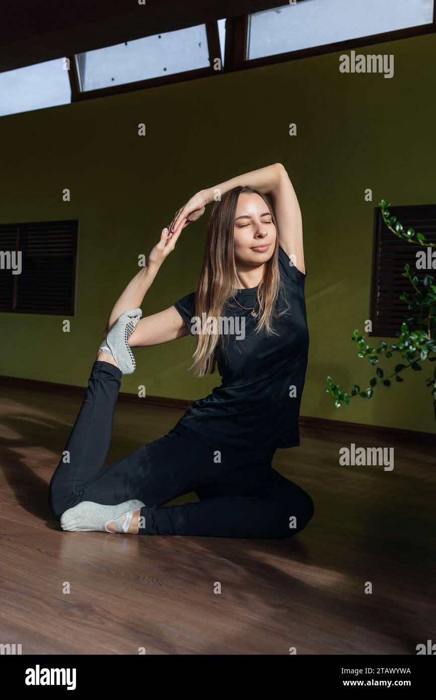 Young attractive woman performs Eka Pada Rajakapotasana exercise ...