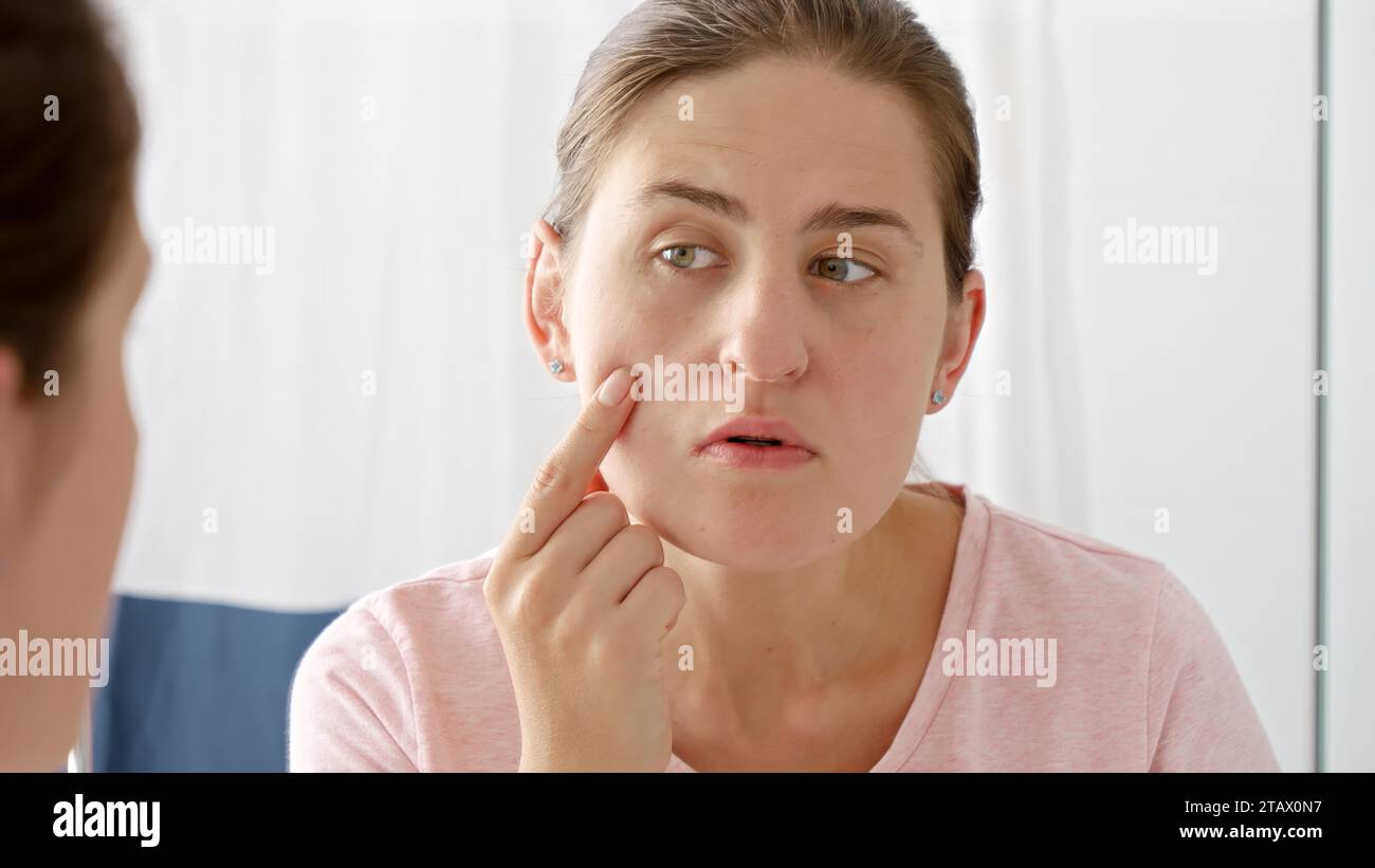 Happy smiling woman looking at her face with pimples. Concept of female ...
