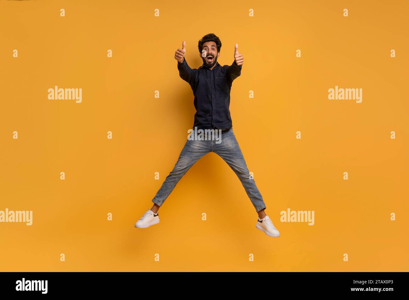 Joyful Indian Man Jumping In Air And Showing Thumbs Up At Camera Stock ...