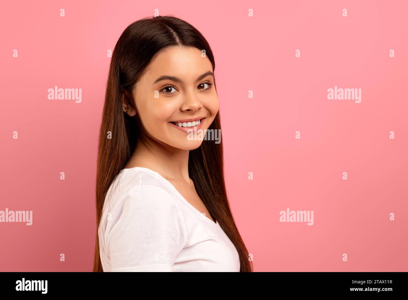 Attractive teen girl with beautiful smile looking over her shoulder at ...