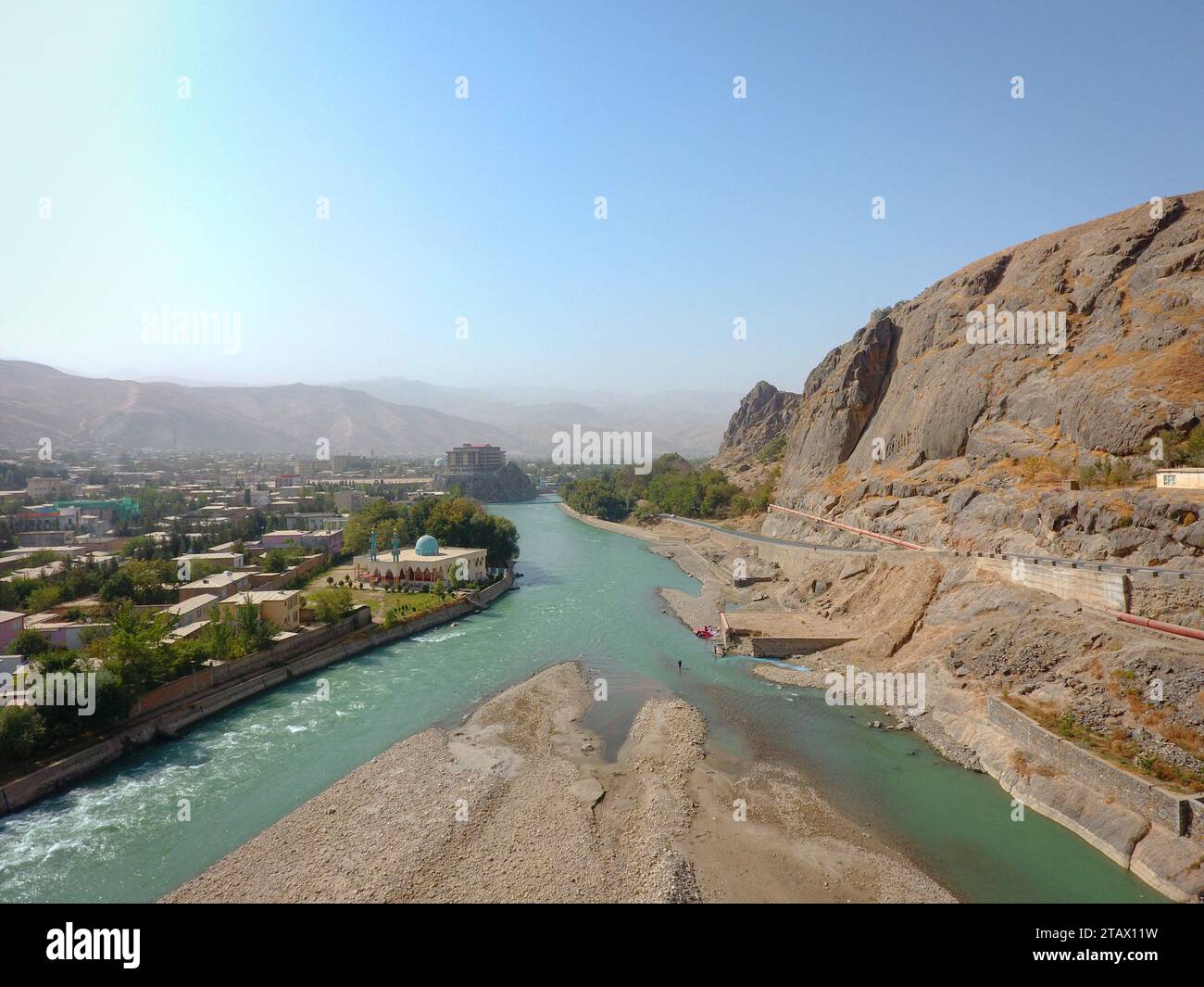 A river flowing through a green village and mountains in Afghanistan ...