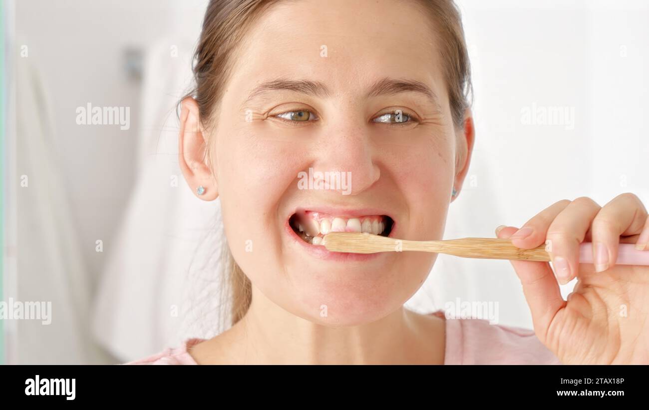 Slow motion shot of young woman brushing her teeth and looking in ...