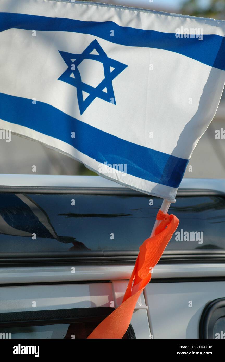 An Israeli flag is attached to a car window along with an orange ...