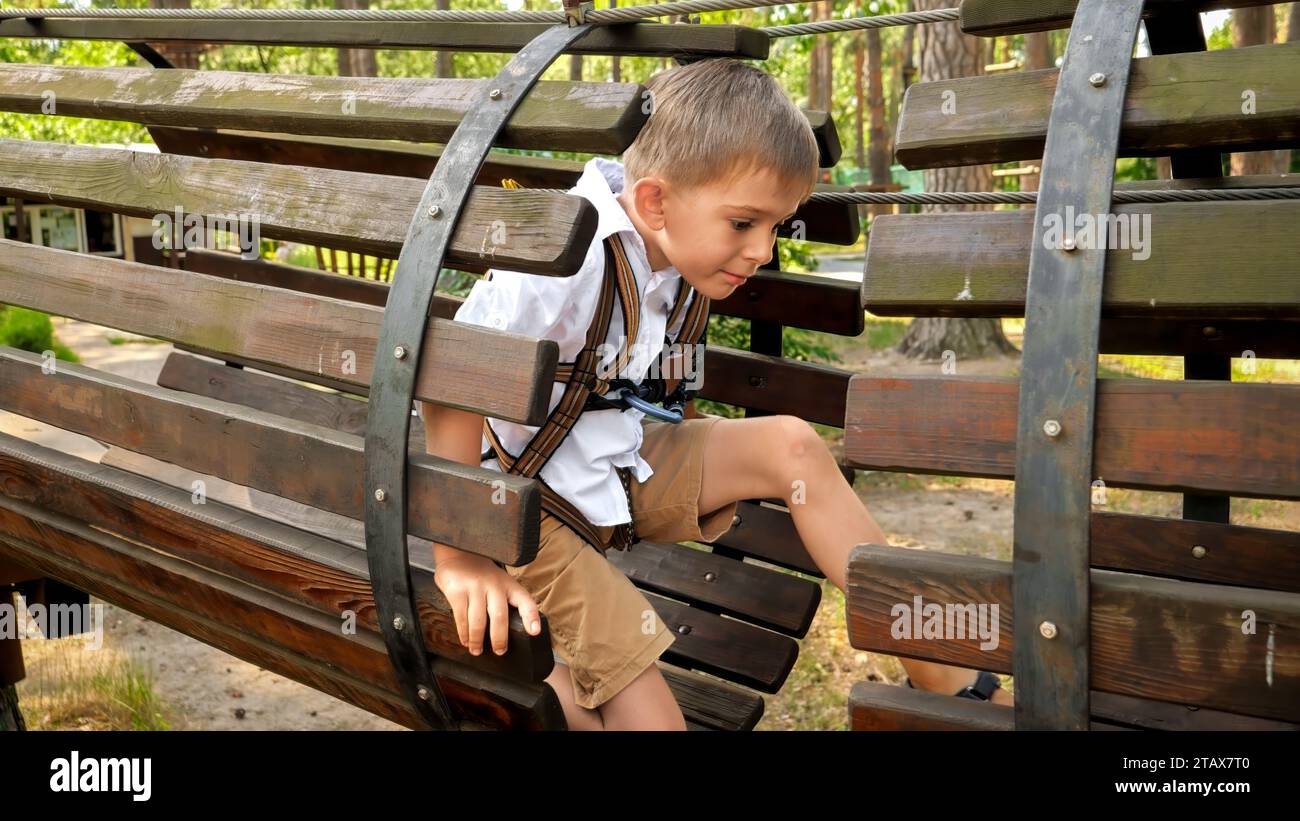 Little boy crawling through wooden pipe or tunnel on playground at park ...