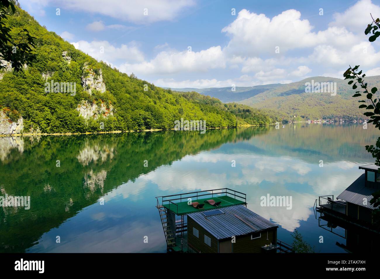 water reflection of fluffy clouds and luxuriant coastline on Perucac ...