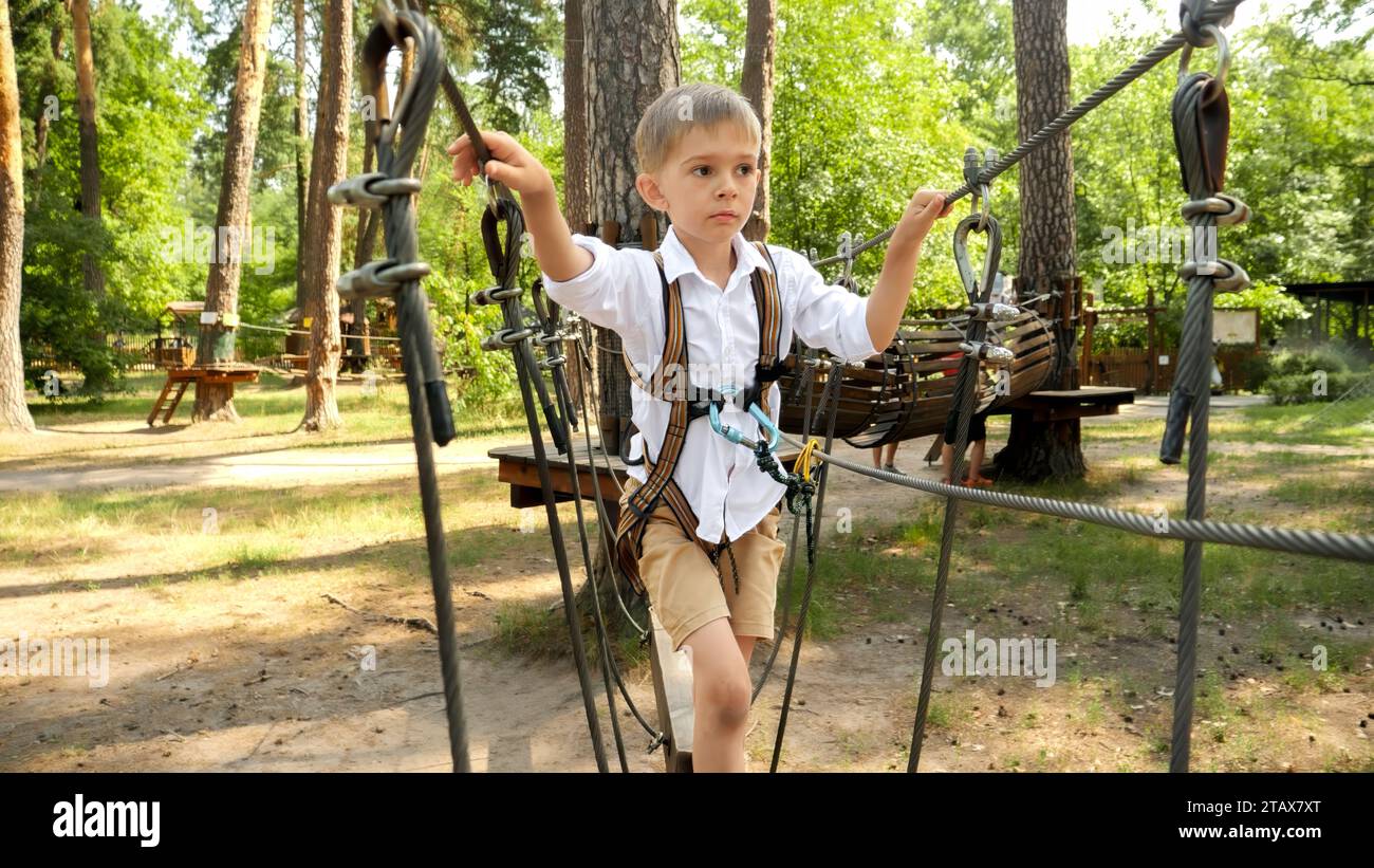 Little boy walking over rope bridge at outdoor amusement park. Active ...