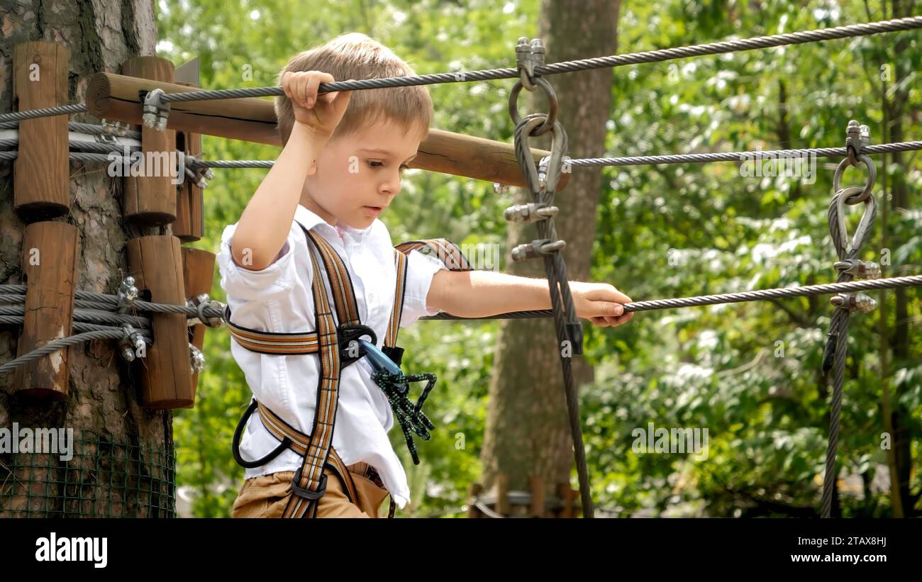 Little boy hooking safety rope before passing obstacles at rope ...