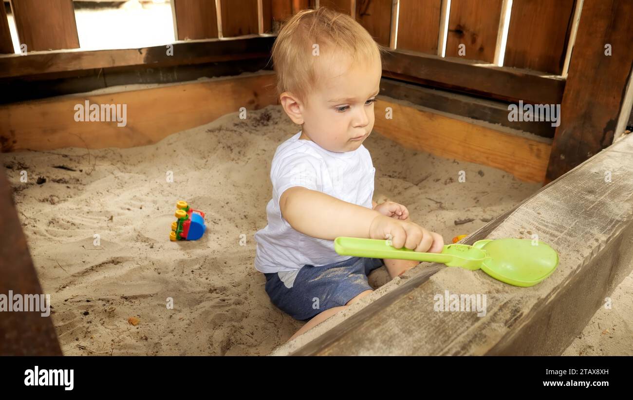 Little boy playing in sandpit with plastic toys and digging sand Stock ... Little boy playing in sandpit with plastic toys and digging sand Stock ...