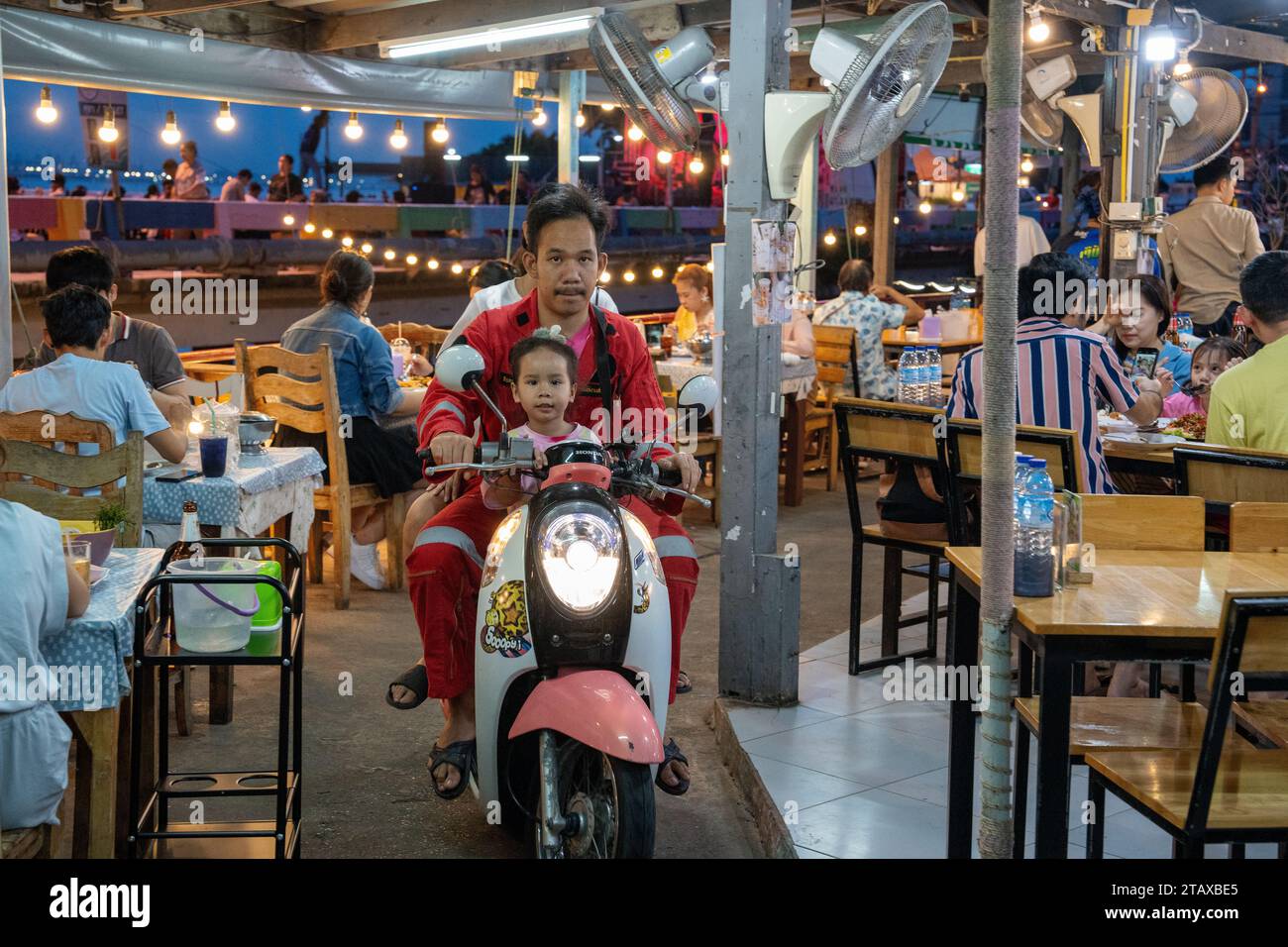 A traditional street restaurant with a narrow passage for scooters in ...