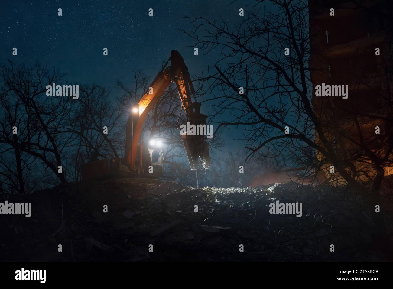 Demolition of a residential building. An excavator with lights ...