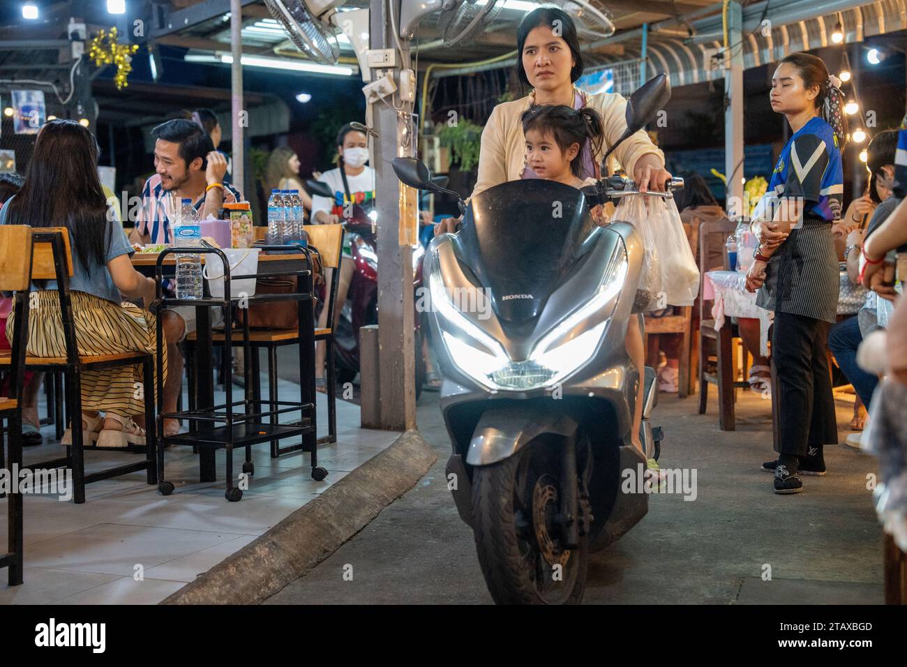 A traditional street restaurant with a narrow passage for scooters in ...