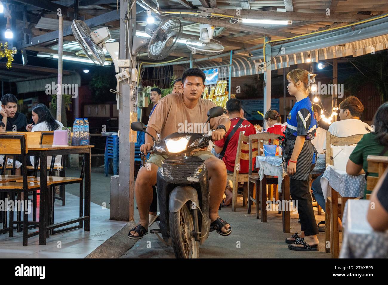 A traditional street restaurant with a narrow passage for scooters in ...