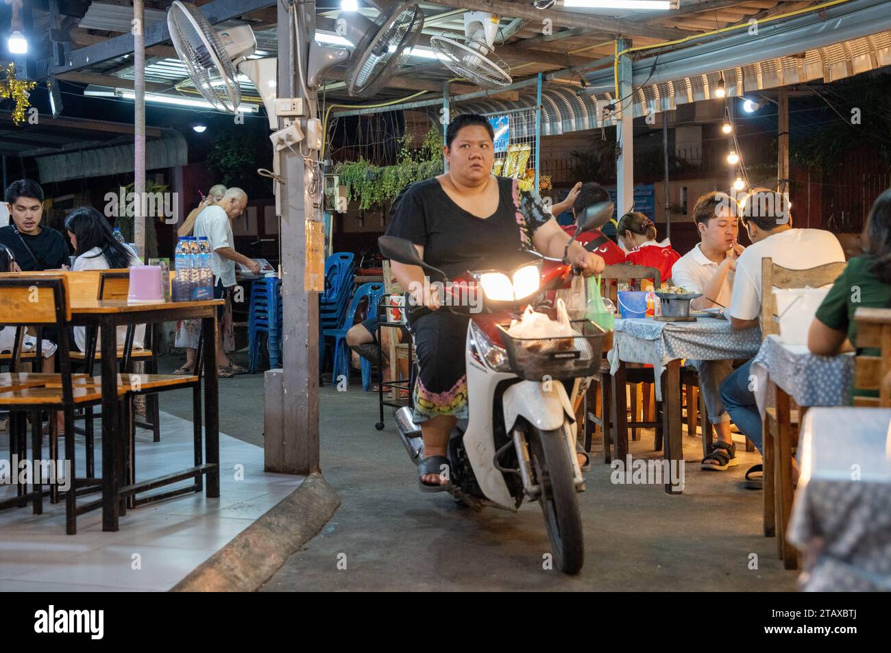 A traditional street restaurant with a narrow passage for scooters in ...