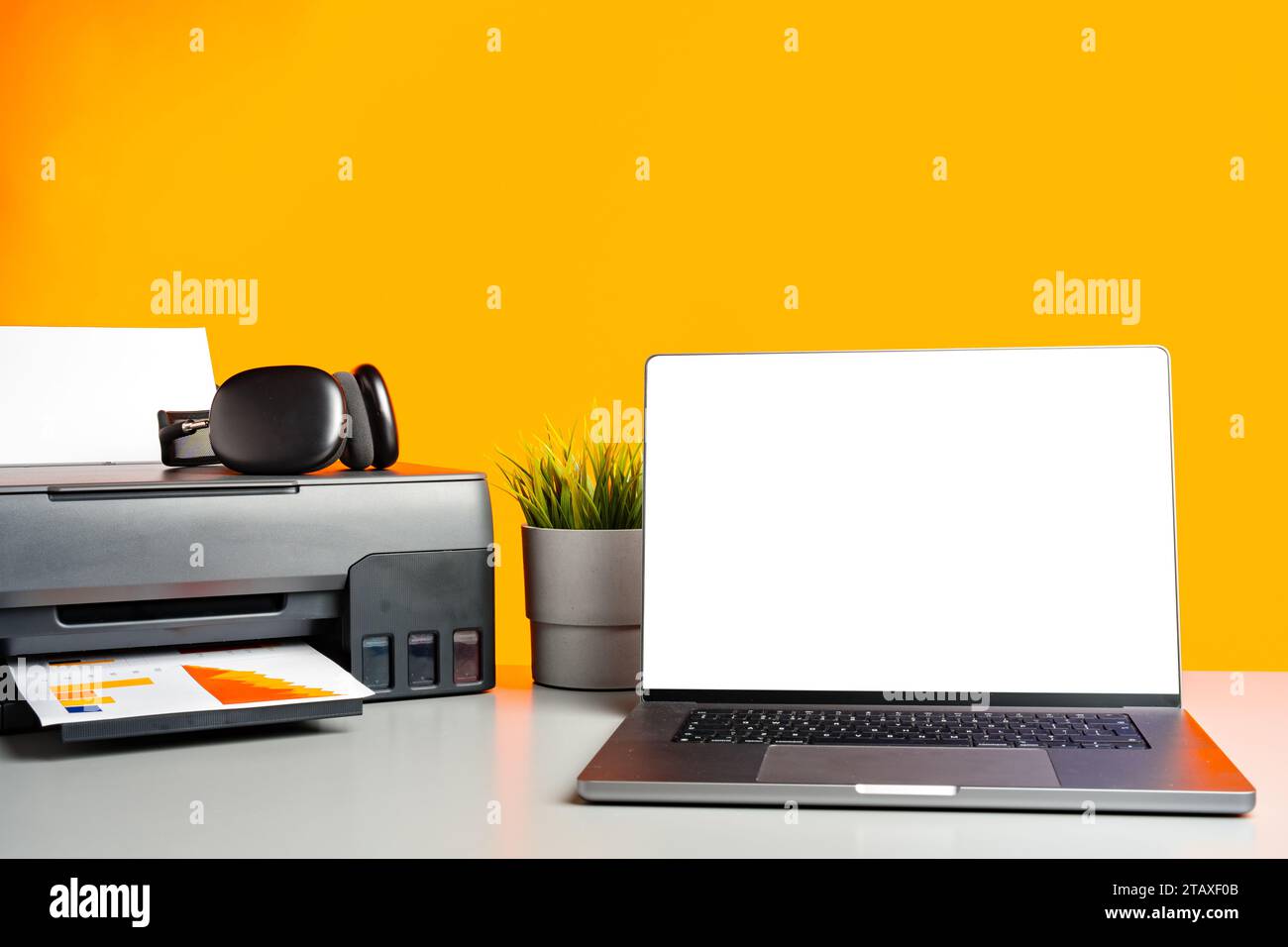 Laser printer and laptop on desk against yellow background Stock Photo ...
