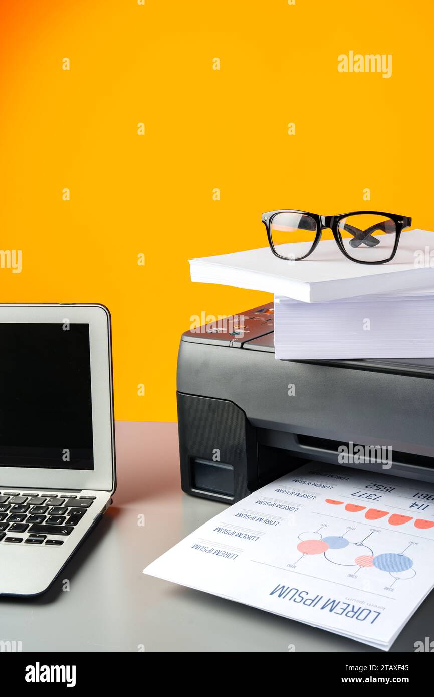 Laser printer and laptop on desk against yellow background Stock Photo ...