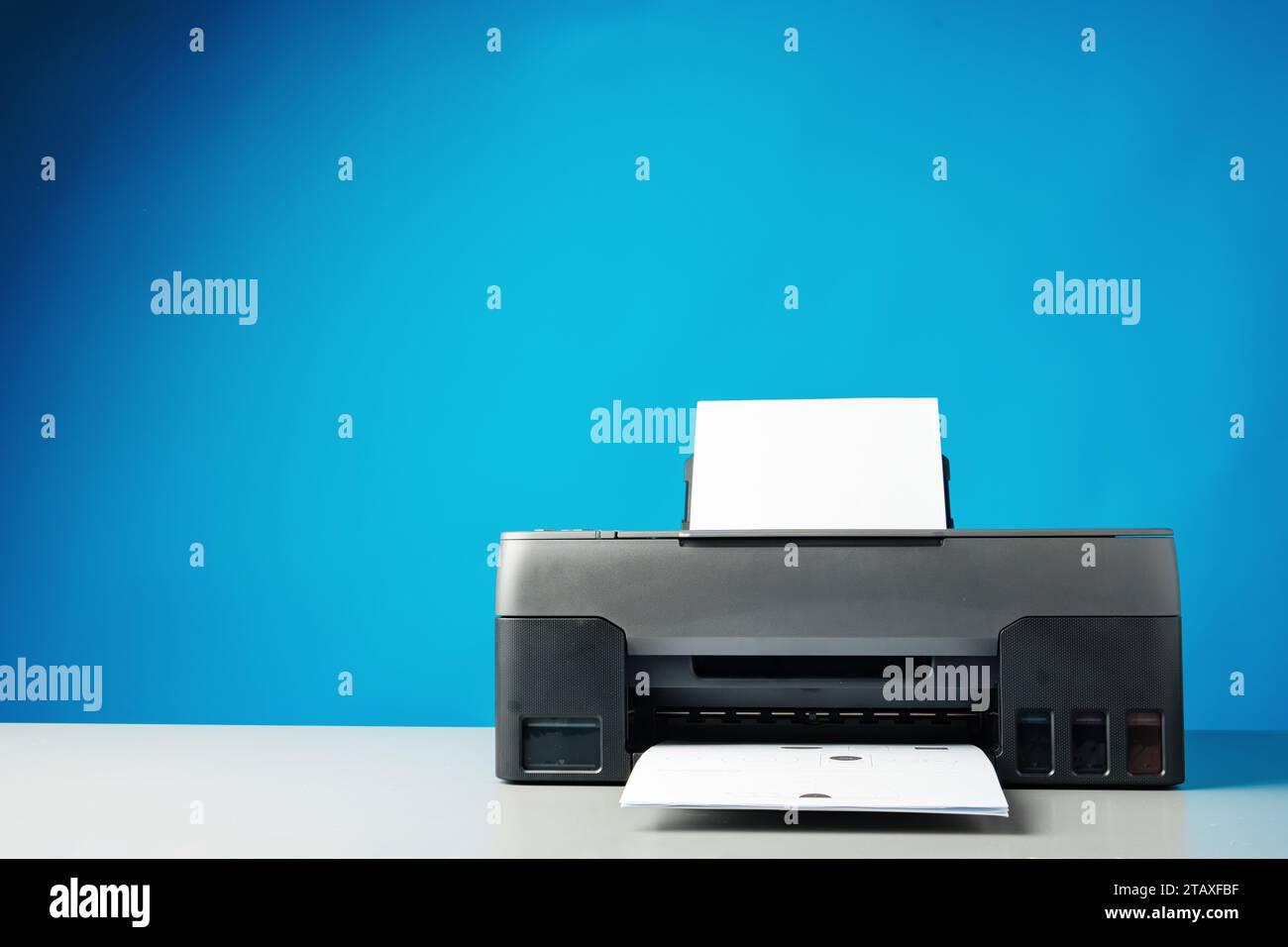 Laser printer on desk against blue background Stock Photo - Alamy