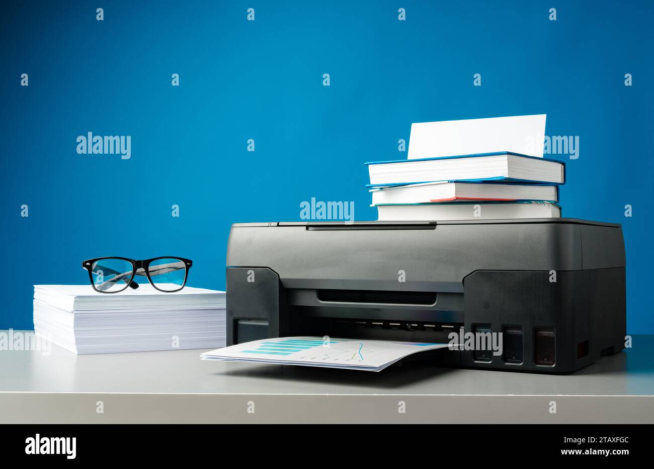 Laser printer on desk against blue background Stock Photo - Alamy