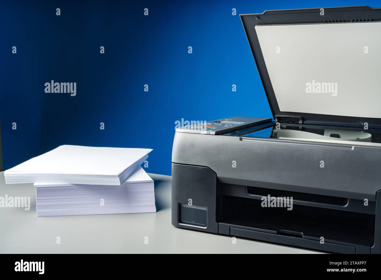 Laser printer on desk against blue background Stock Photo - Alamy