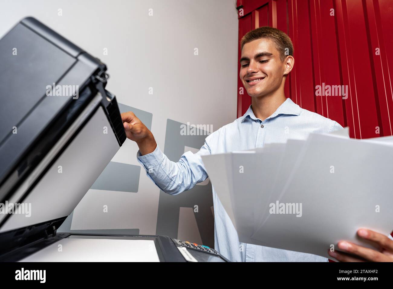 Positive young man using printer in the modern office Stock Photo - Alamy
