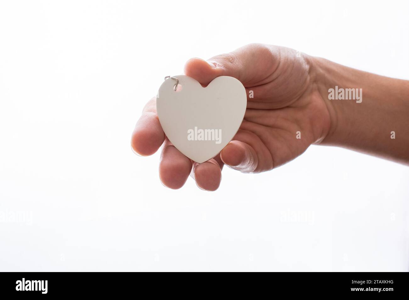 Heart shaped white object in hand on white background Stock Photo - Alamy
