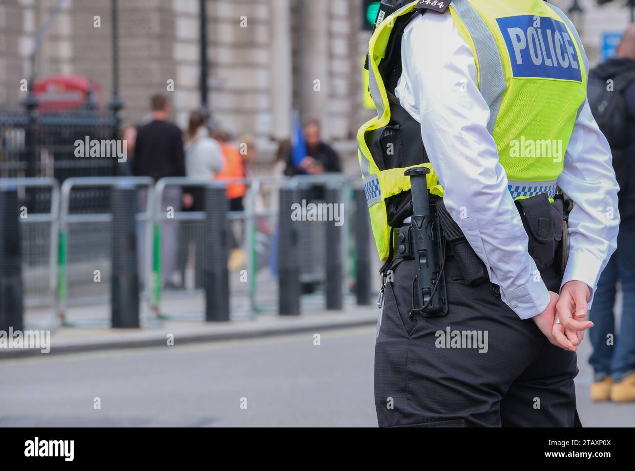 Metropolitan Police officer wearing a high visibility vest, escorting ...