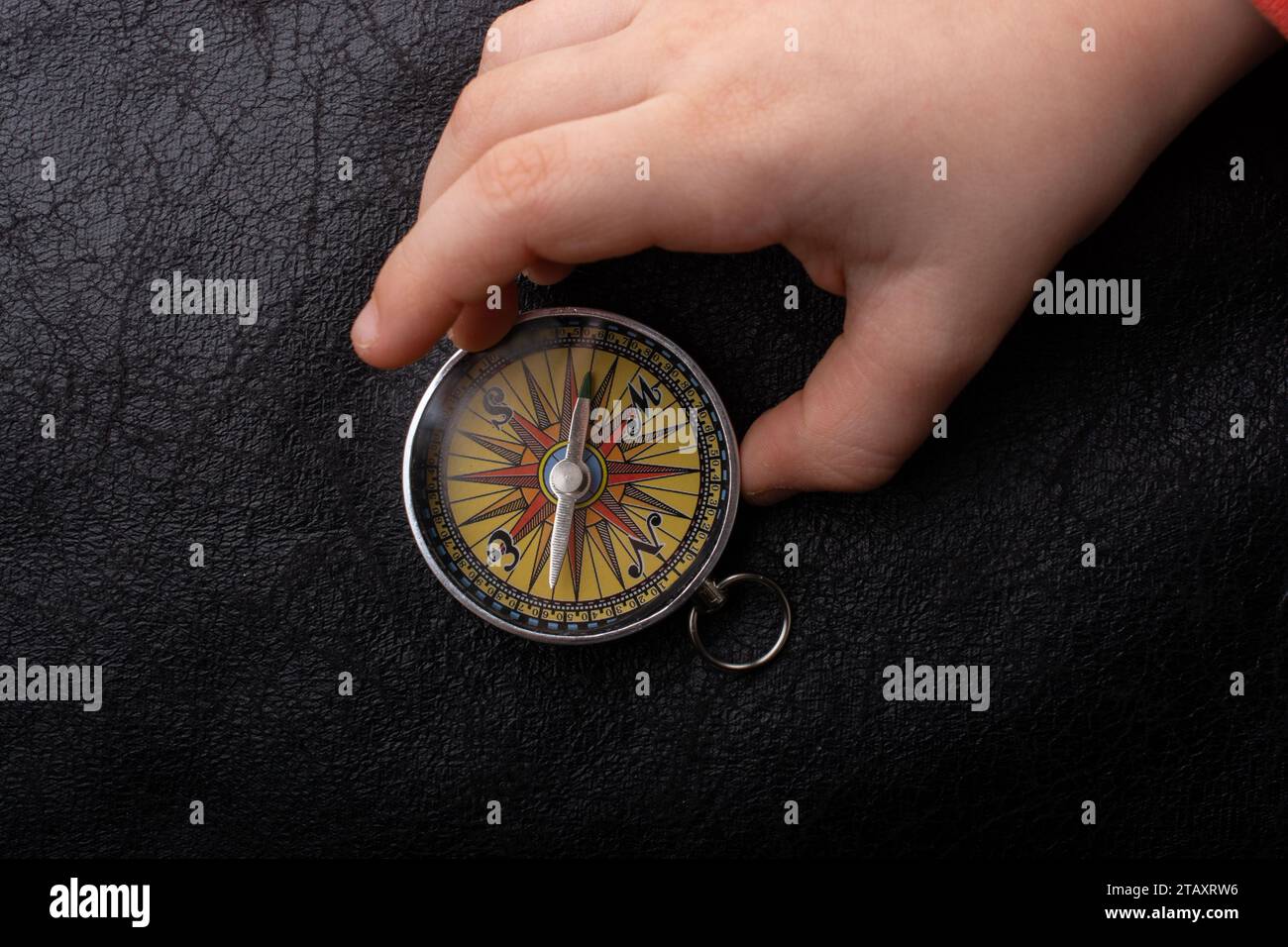 Hand is holding a magnetic compass on black background Stock Photo - Alamy