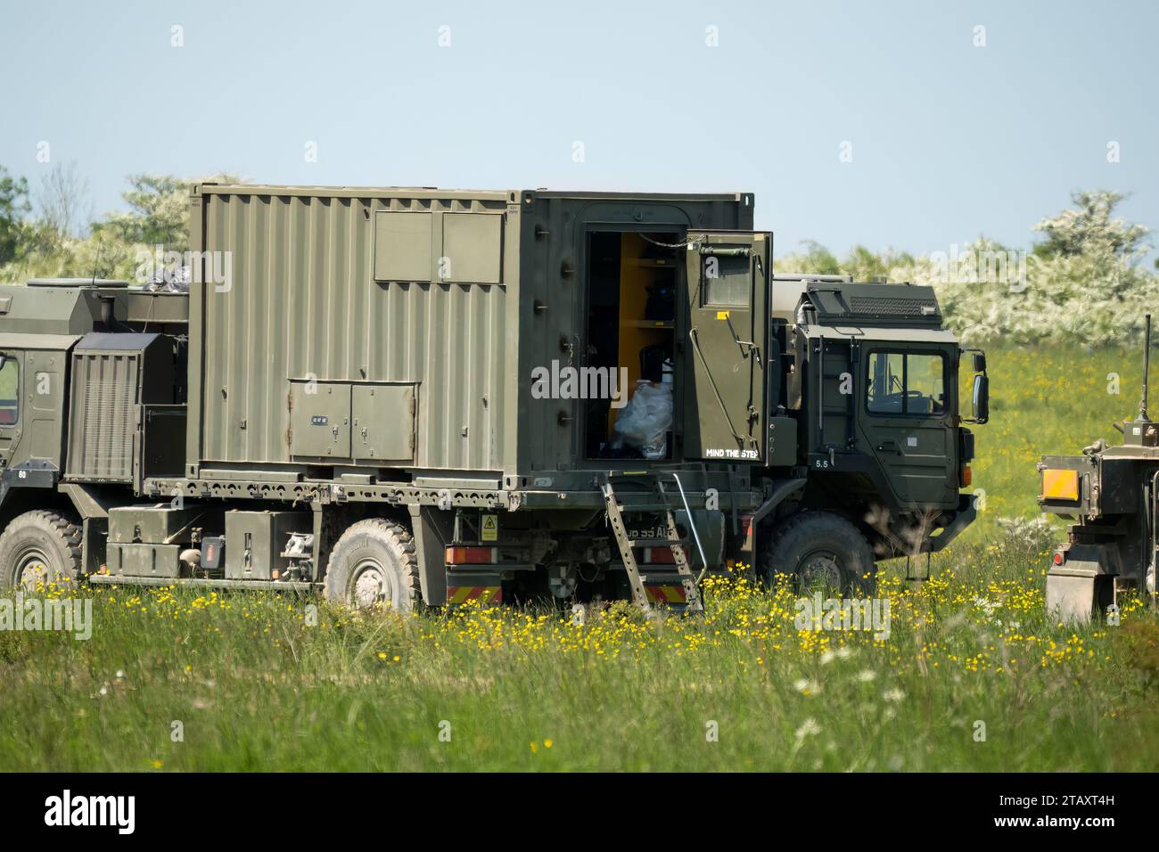 dark green logistics vehicles in a long grass field Stock Photo - Alamy