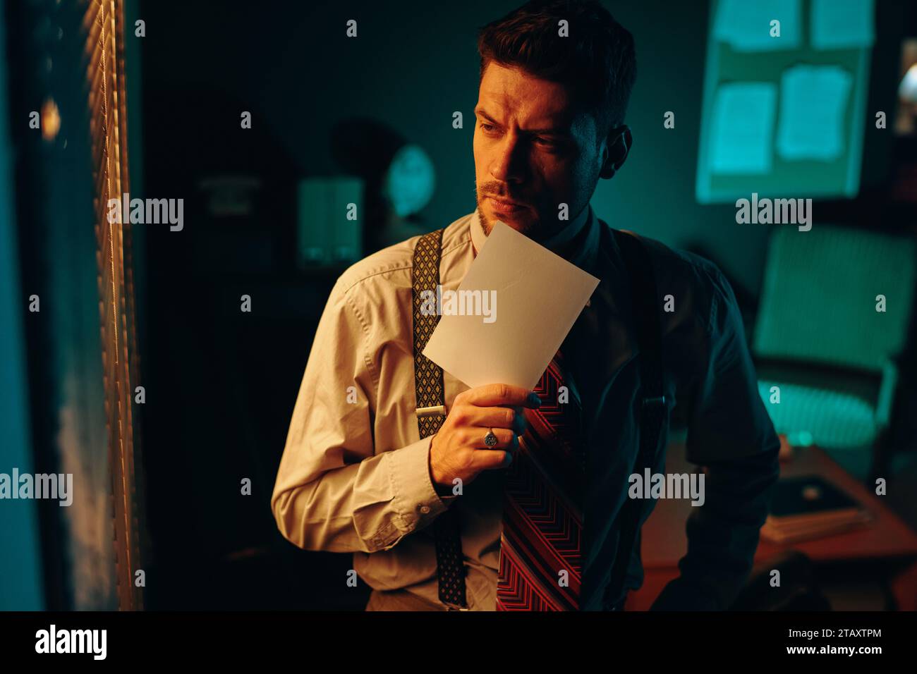 Young pensive retro male officer or detective with photo by his face ...