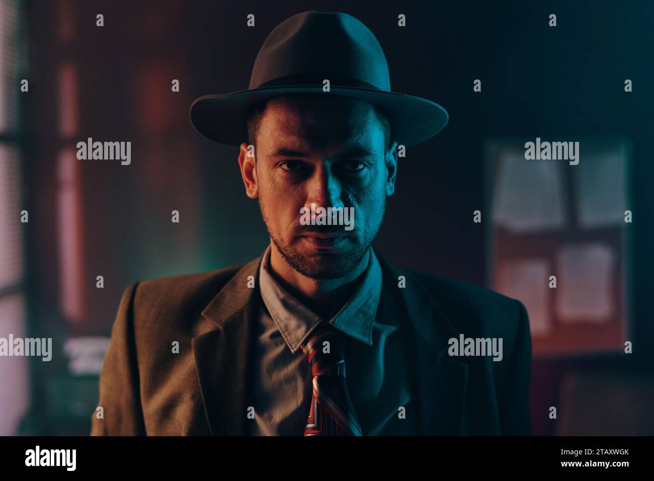 Portrait of young serious male spy or detective officer in hat and ...