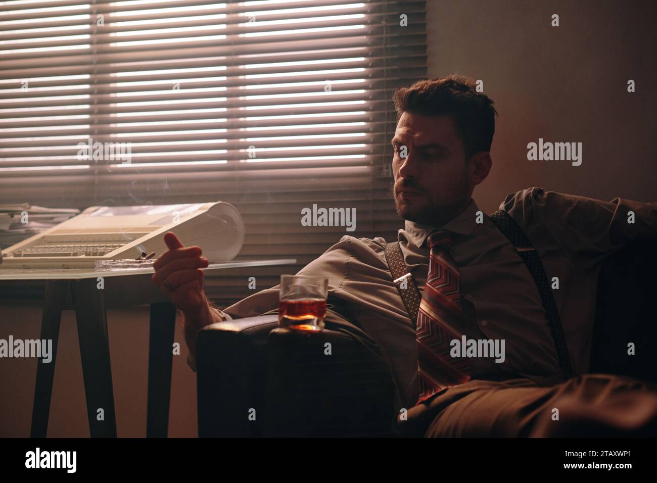 Young restful man in formalwear sitting on comfortable black leather ...