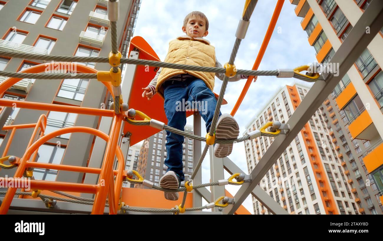 Little active boy walking over rope bridge on modern children ...
