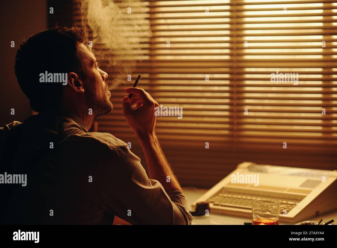 Young inspired man smoking cigarette and looking through window with ...