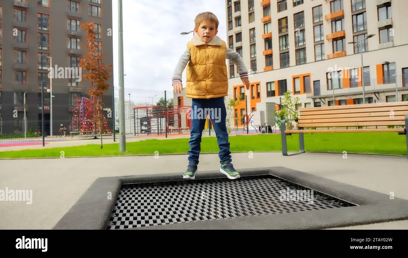 Active laughing boy jumping up high on the trampoline and having fun ...