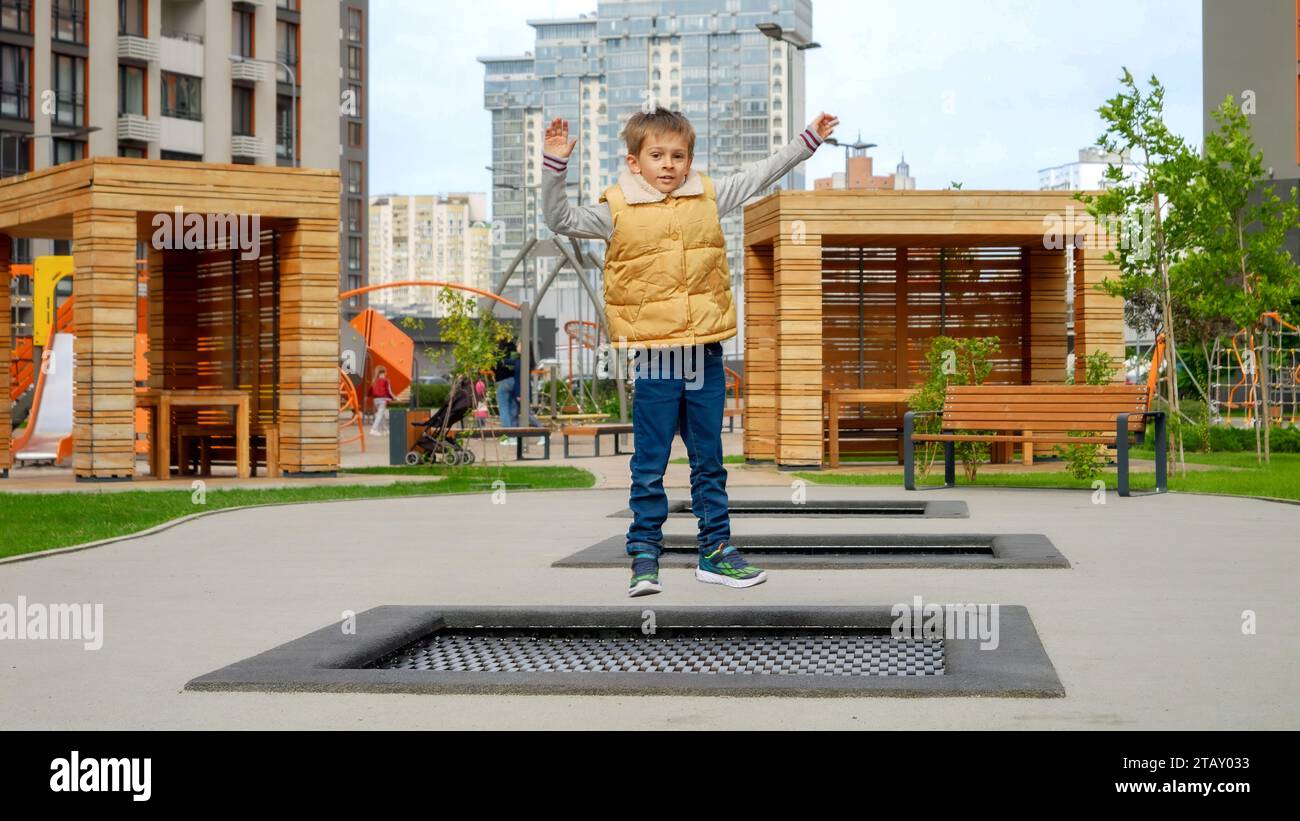 Happy laughing boy jumping high on trampoline at newly built public ...
